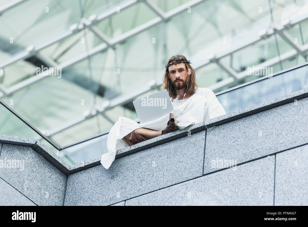 low angle view of serious Jesus in robe and crown of thorns using ...