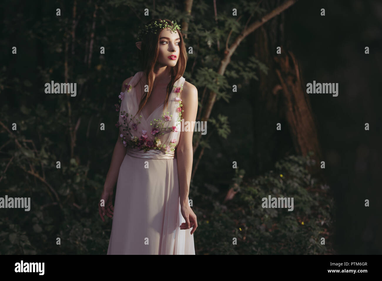 beautiful mystic elf in flower dress and floral wreath in woods Stock ...