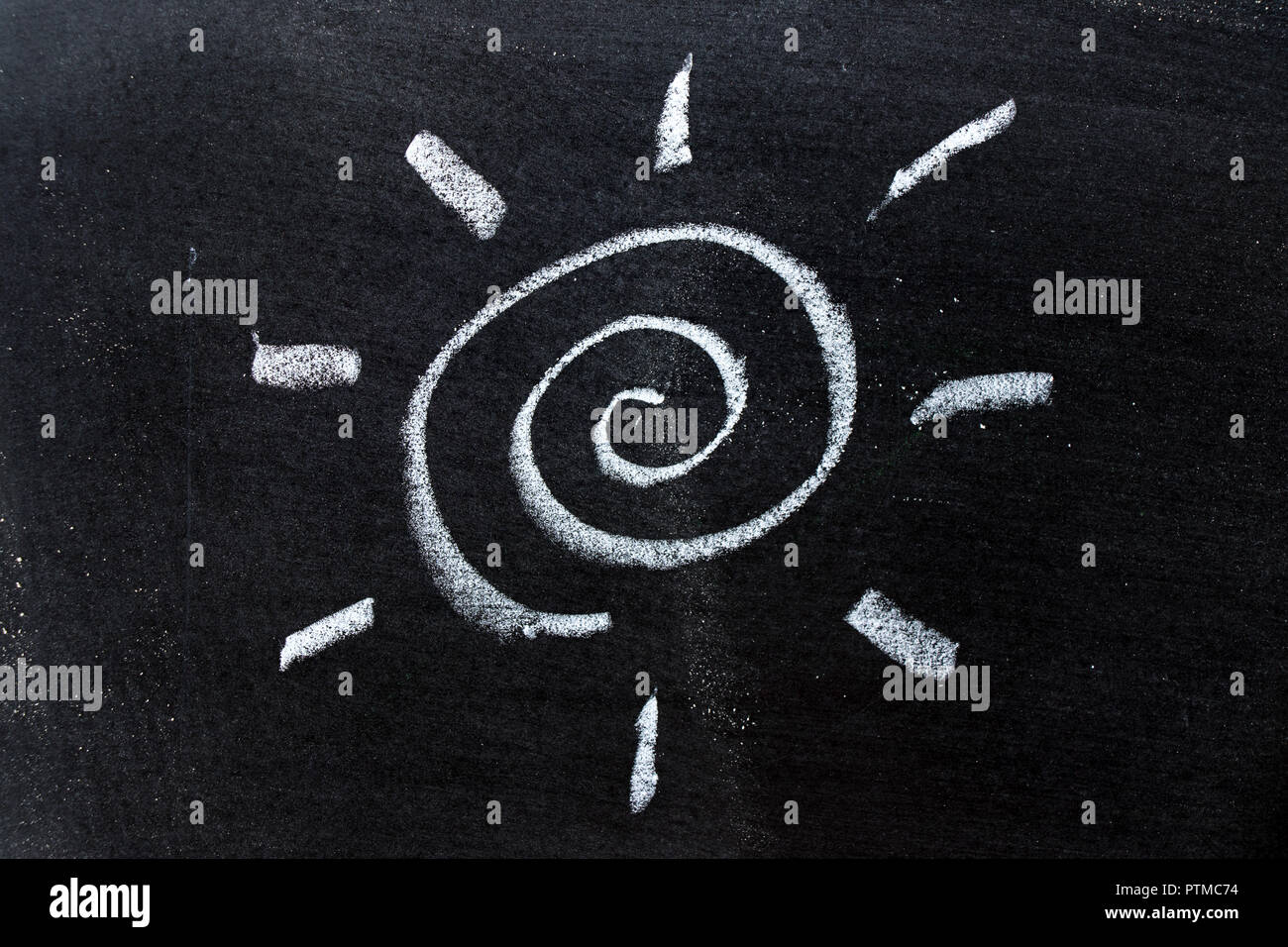 White color chalk hand drawing as sun with light ray shape on black ...