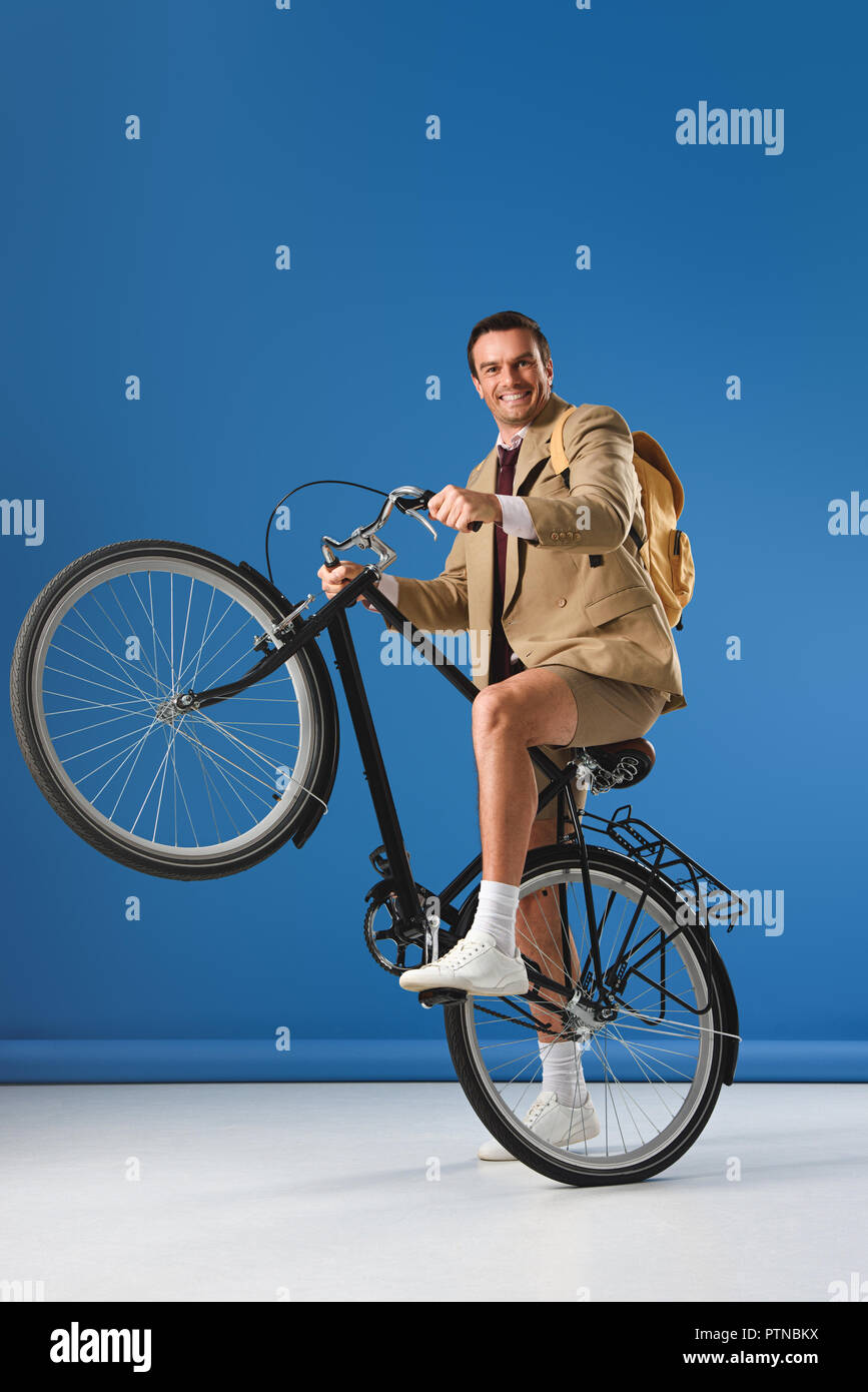 happy man riding bicycle and smiling at camera on blue Stock Photo - Alamy