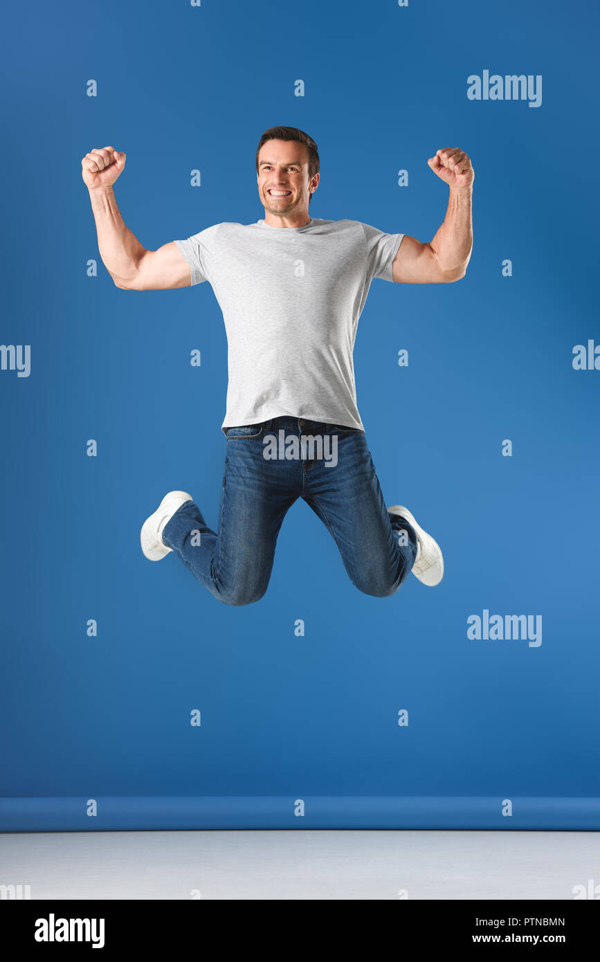 excited man jumping and triumphing on blue Stock Photo - Alamy