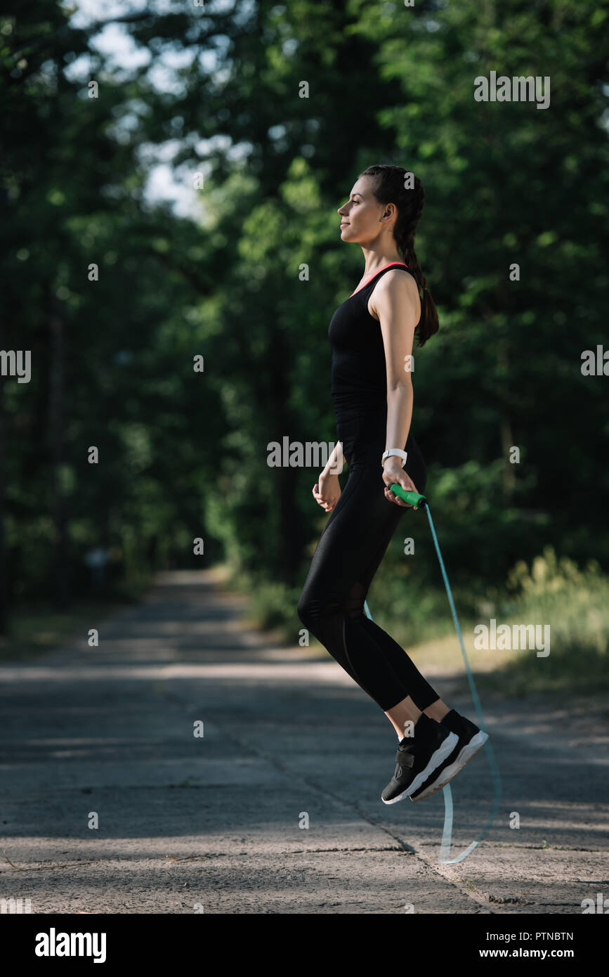 beautiful athletic girl jumping on skipping rope on path in park Stock ...