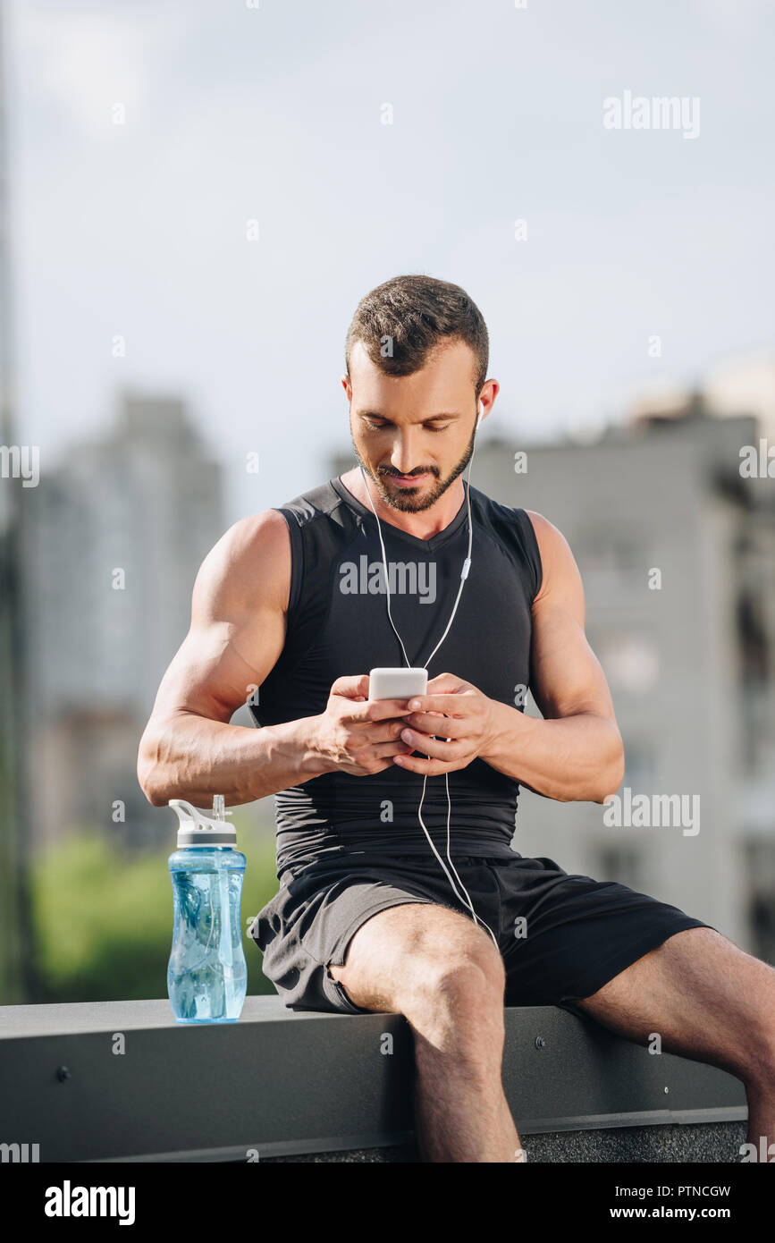 handsome sportsman listening music and using smartphone on roof Stock ...