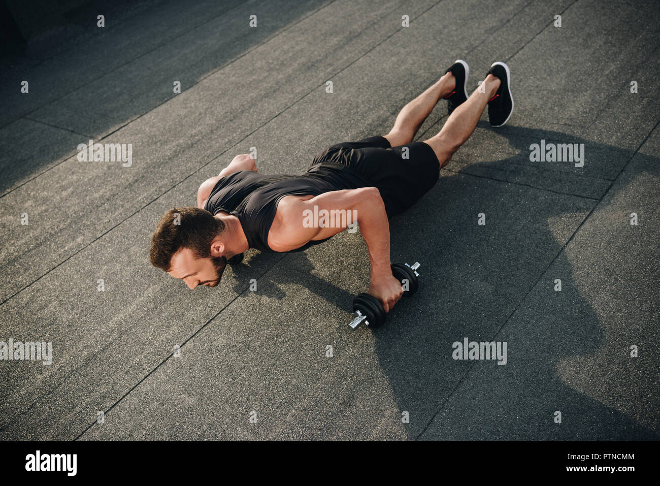 high angle view of handsome sportsman doing push ups with dumbbells on ...