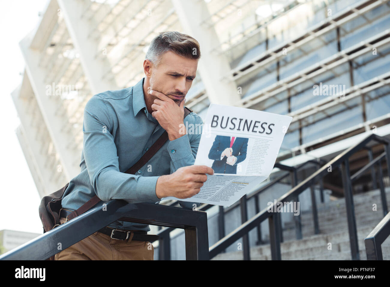 thoughtful middle aged man leaning at railing and reading business ...