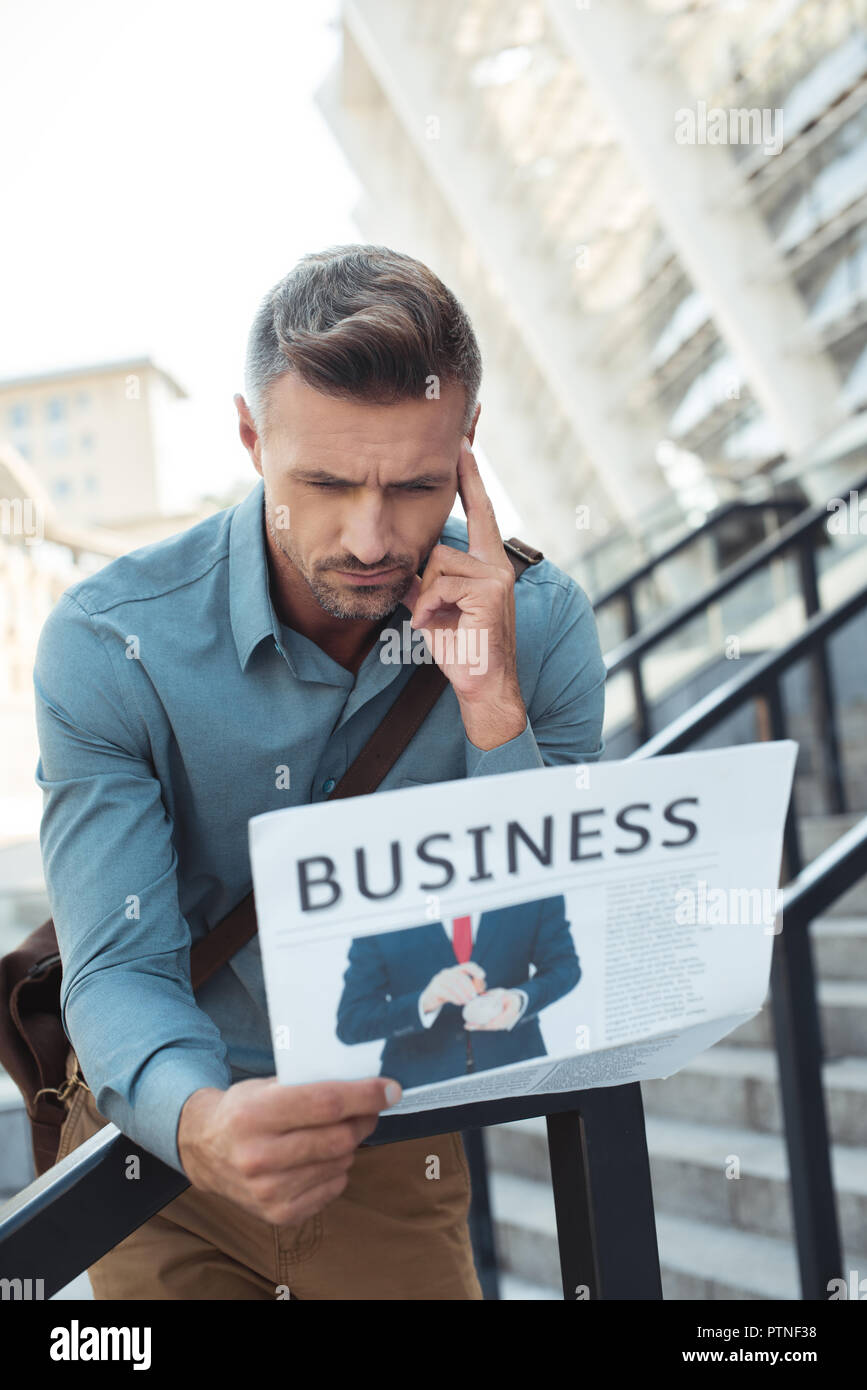 focused middle aged man leaning at railing and reading business ...