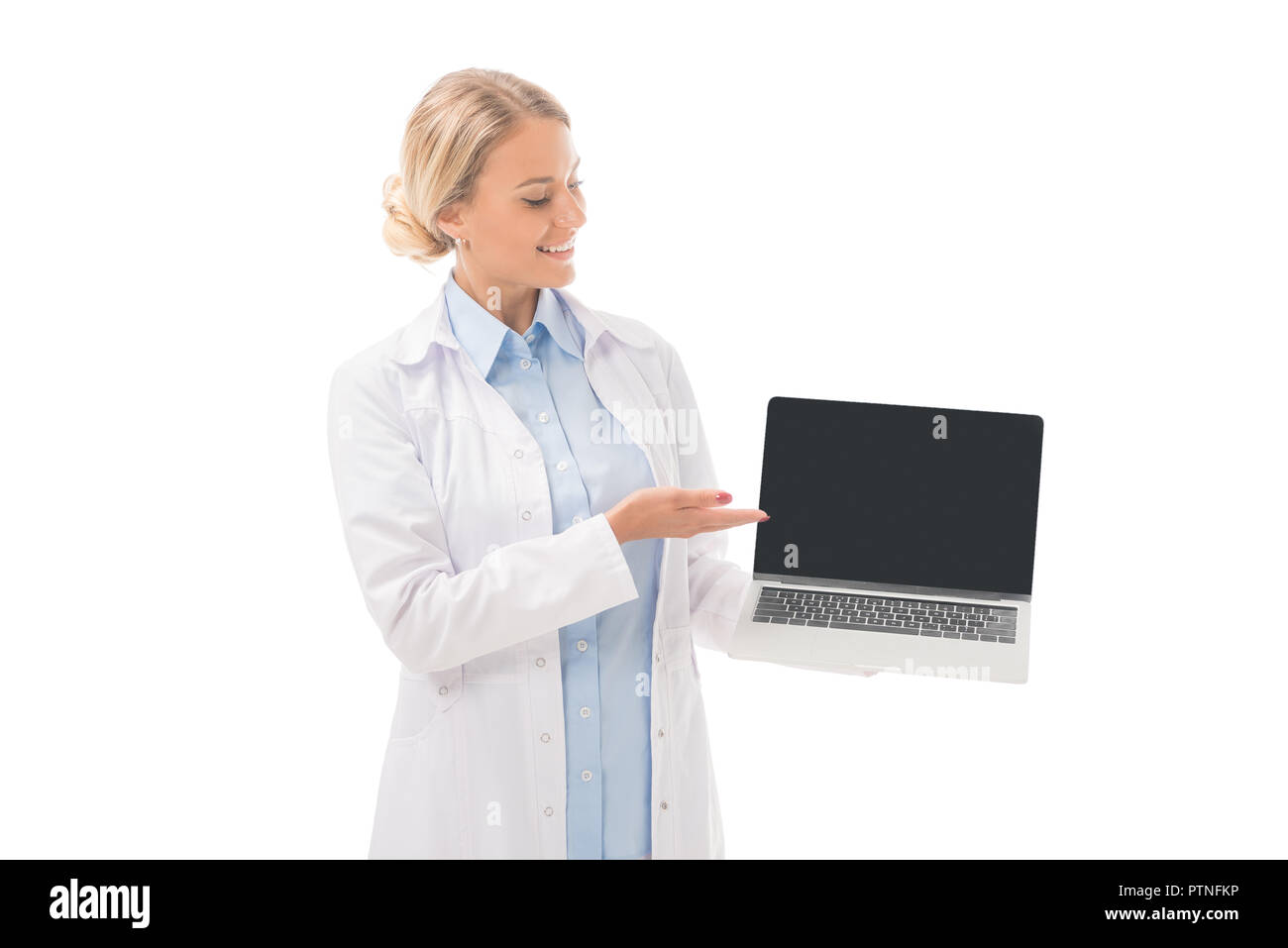 smiling young female doctor pointing at laptop with blank screen ...