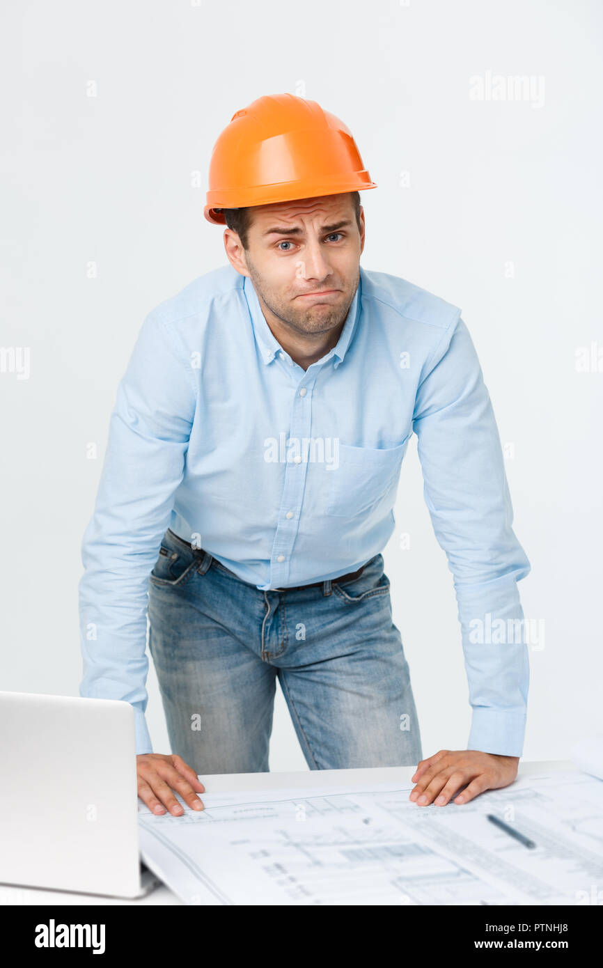 Young man wearing architect outfit and helmet with angry face, negative ...