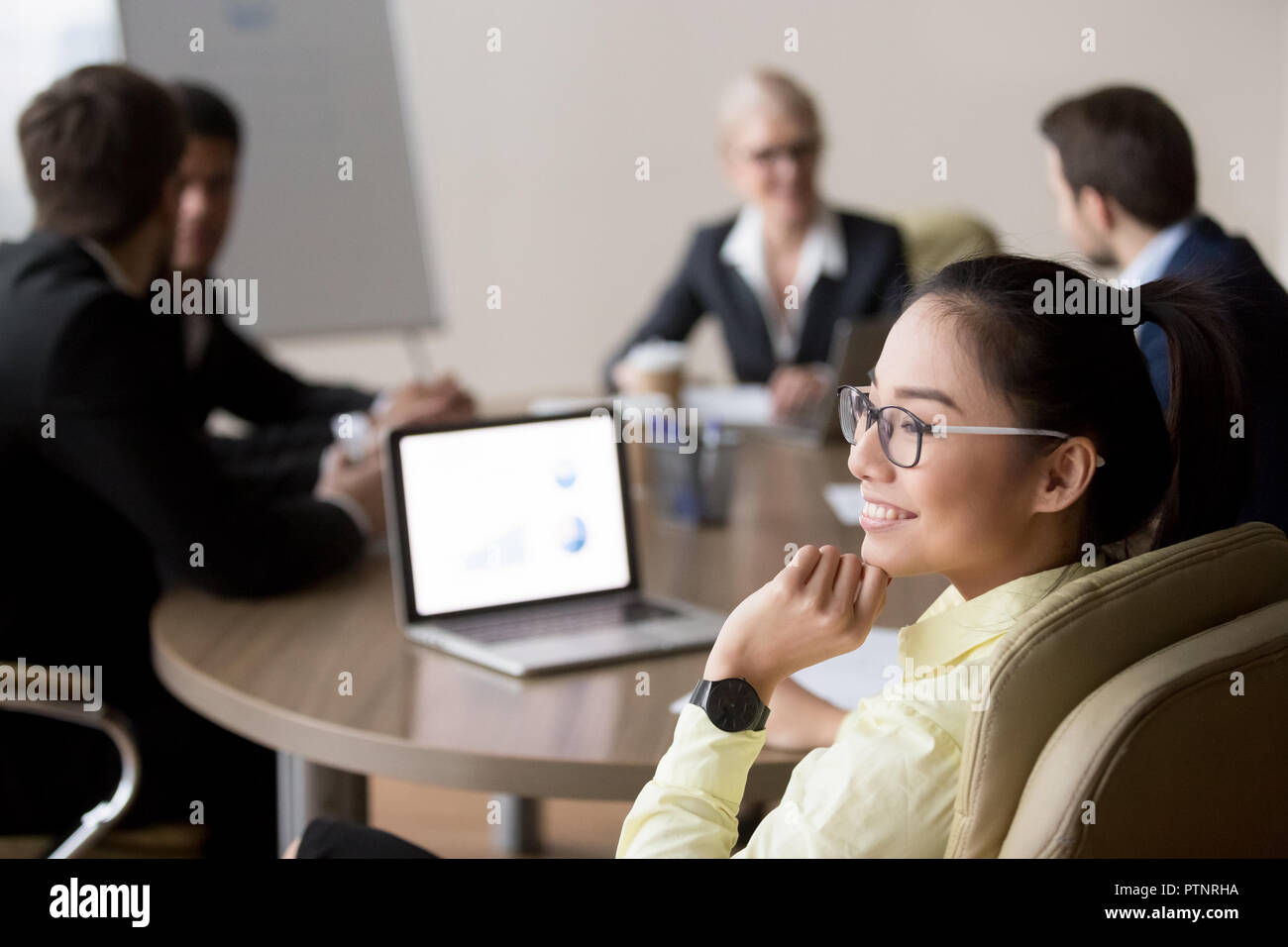 Smiling Asian employee distracted from meeting dreaming of somet Stock ...