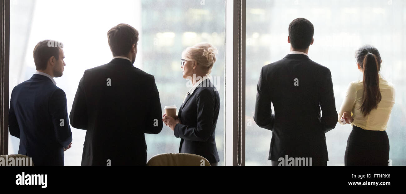 Back view of colleagues standing near window enjoying coffee bre Stock ...