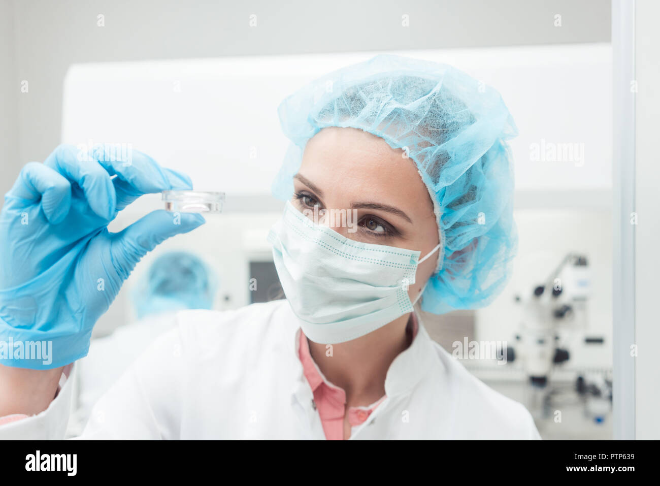 Woman scientist showing her newest biotech experiment in lab petri dish ...
