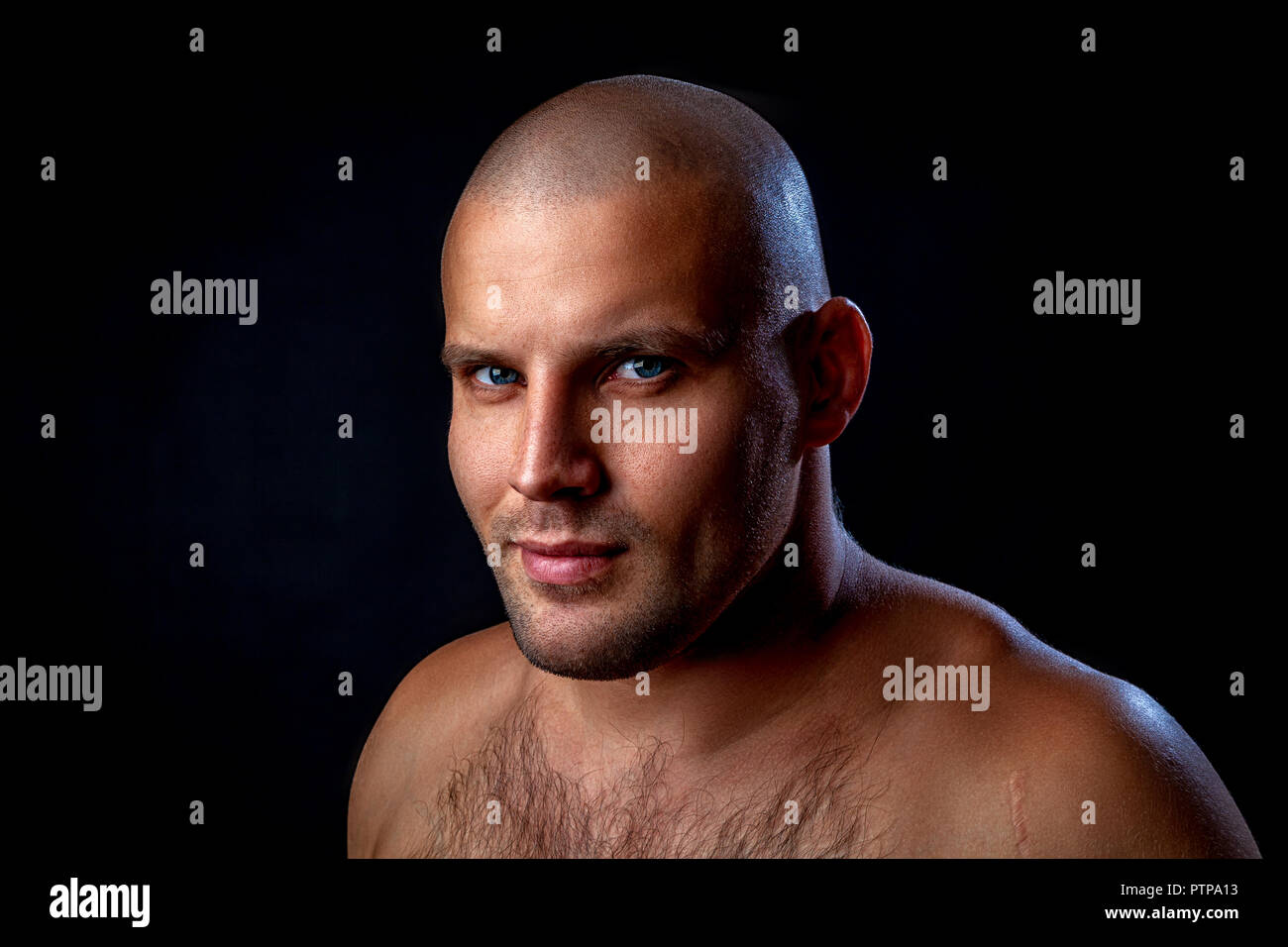 Smiling young bald man standing isolated on a black background and ...