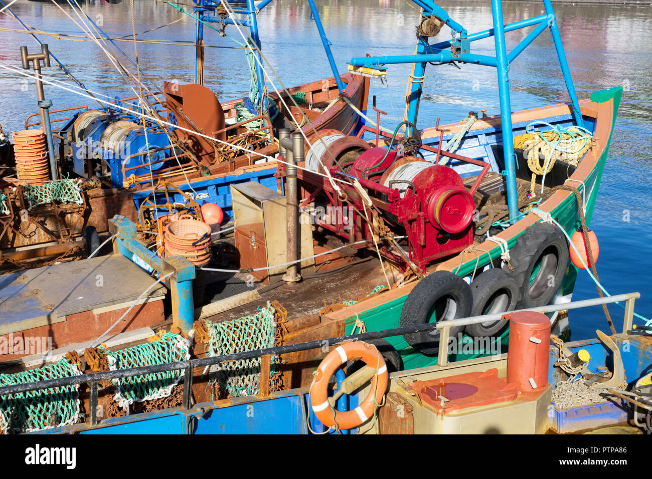 Trawler fishing boat bright colours lit by sunshine at harbour port ...