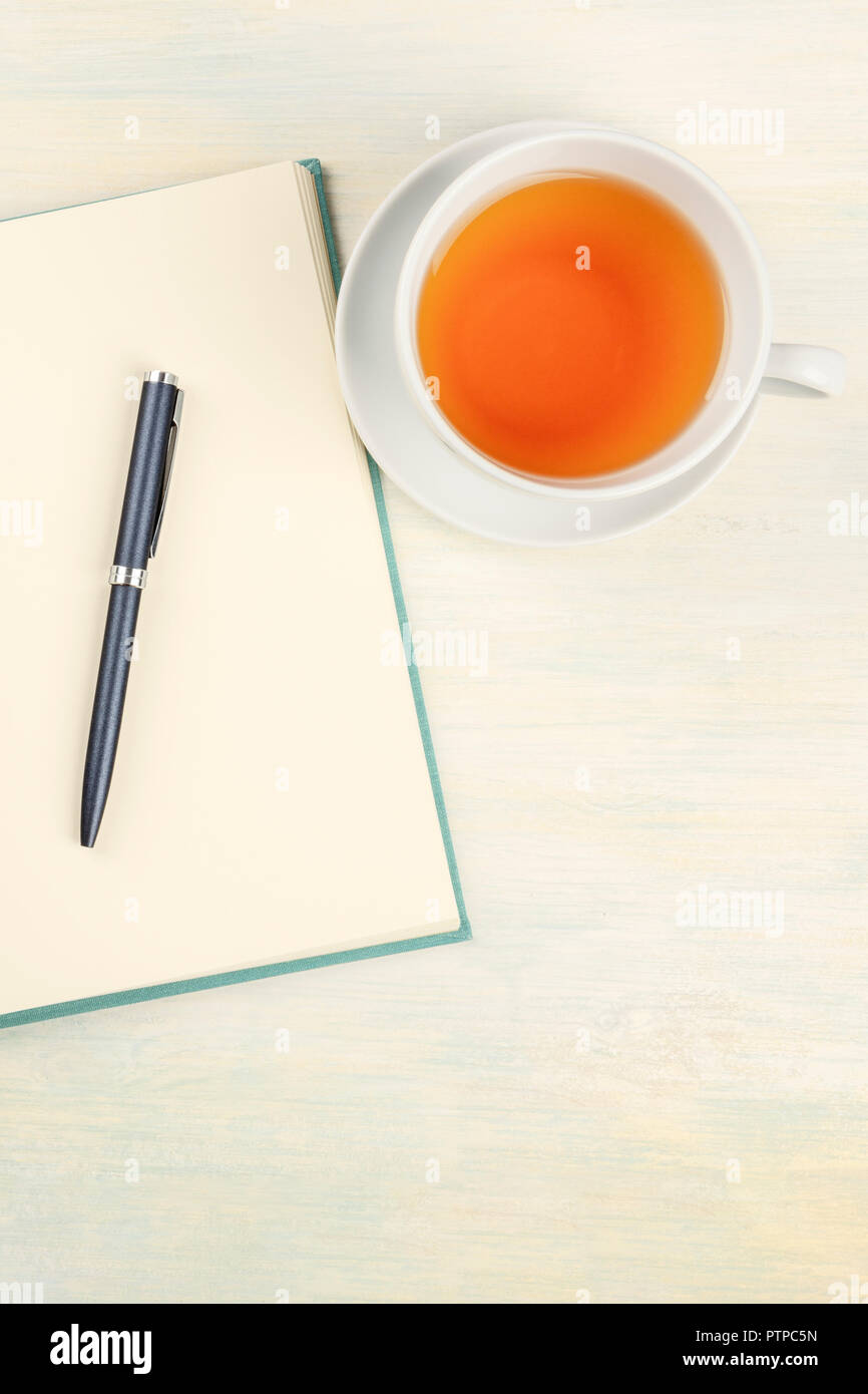 An overhead photo of an open journal with a pen and a cup of tea, shot ...