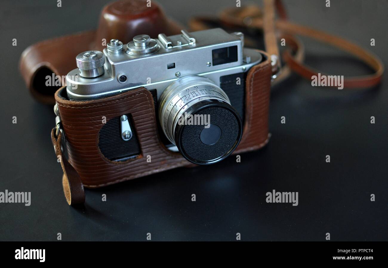 Vintage old film camera with brown leather case, on black background ...