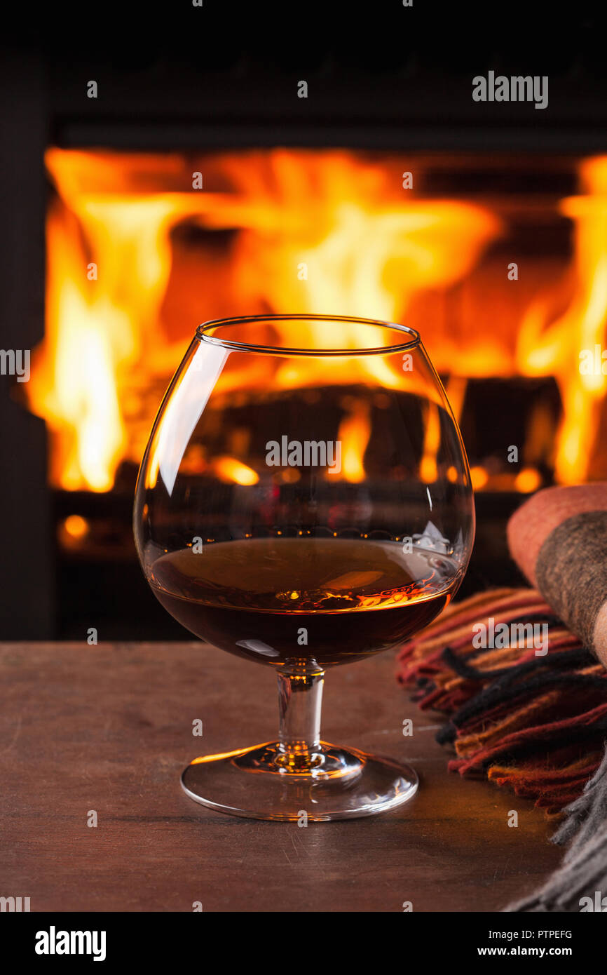 glass of cognac in front of fireplace Stock Photo - Alamy