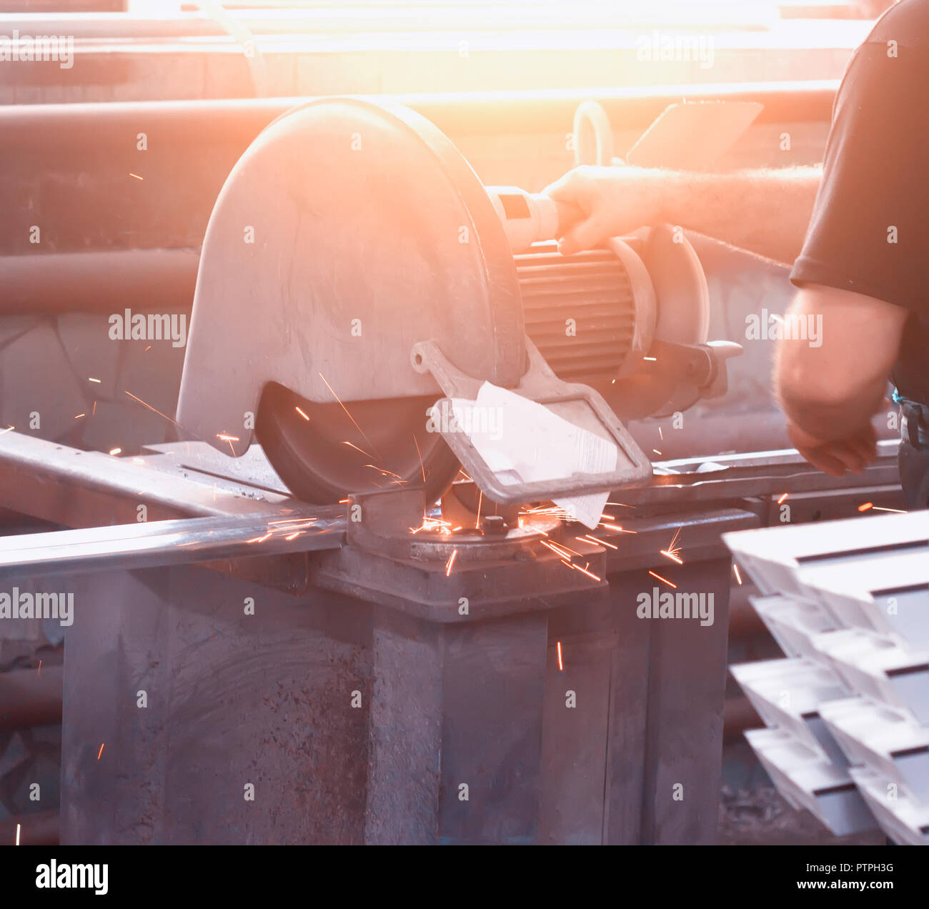 Production of pvc windows, a man cuts a metal profile on a circular saw ...