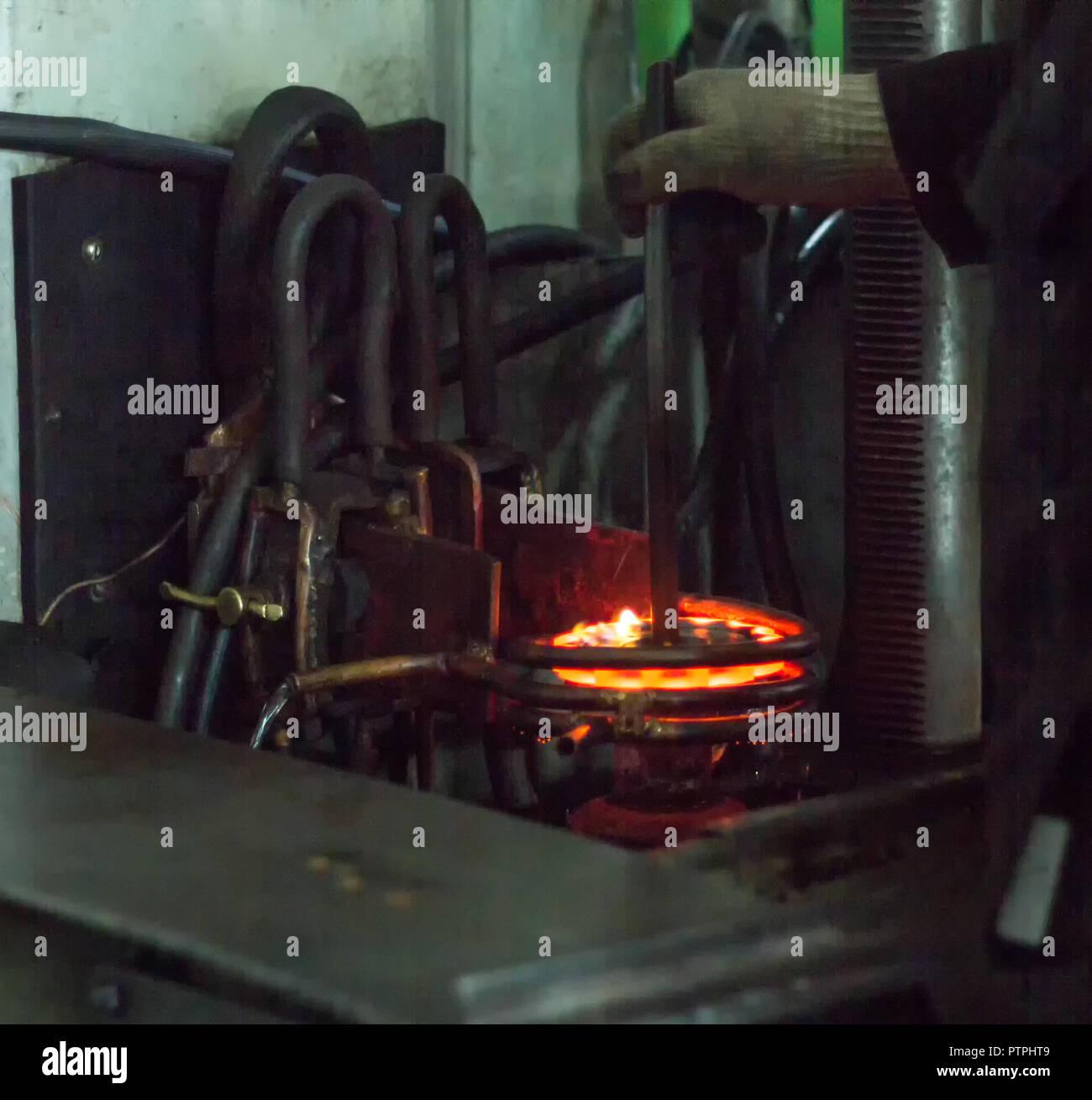 The worker makes hardening heat treatment of the metal gear on a ...