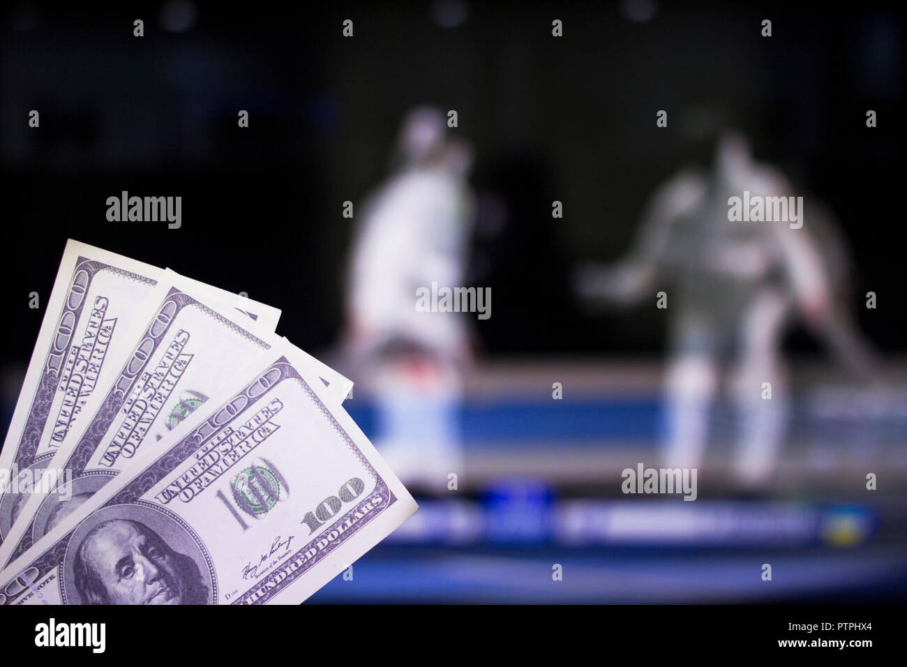 Money dollars on the background of a TV on which show sport fencing ...
