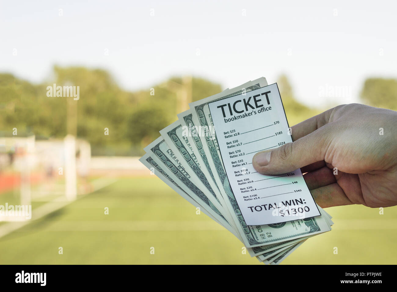 Male hand holding money dollars and bookmaker ticket against the ...