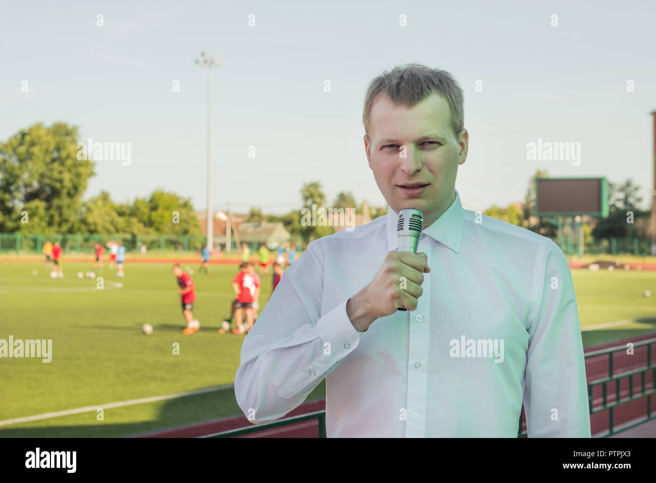 A male commentator in a white shirt with a microphone comments on ...