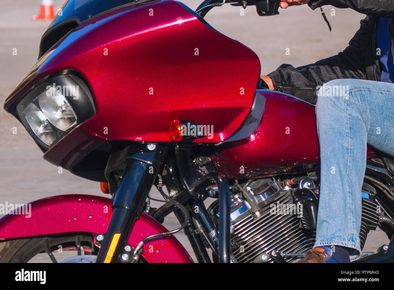 Biker in jeans riding a red motorcycle. Side view Stock Photo - Alamy