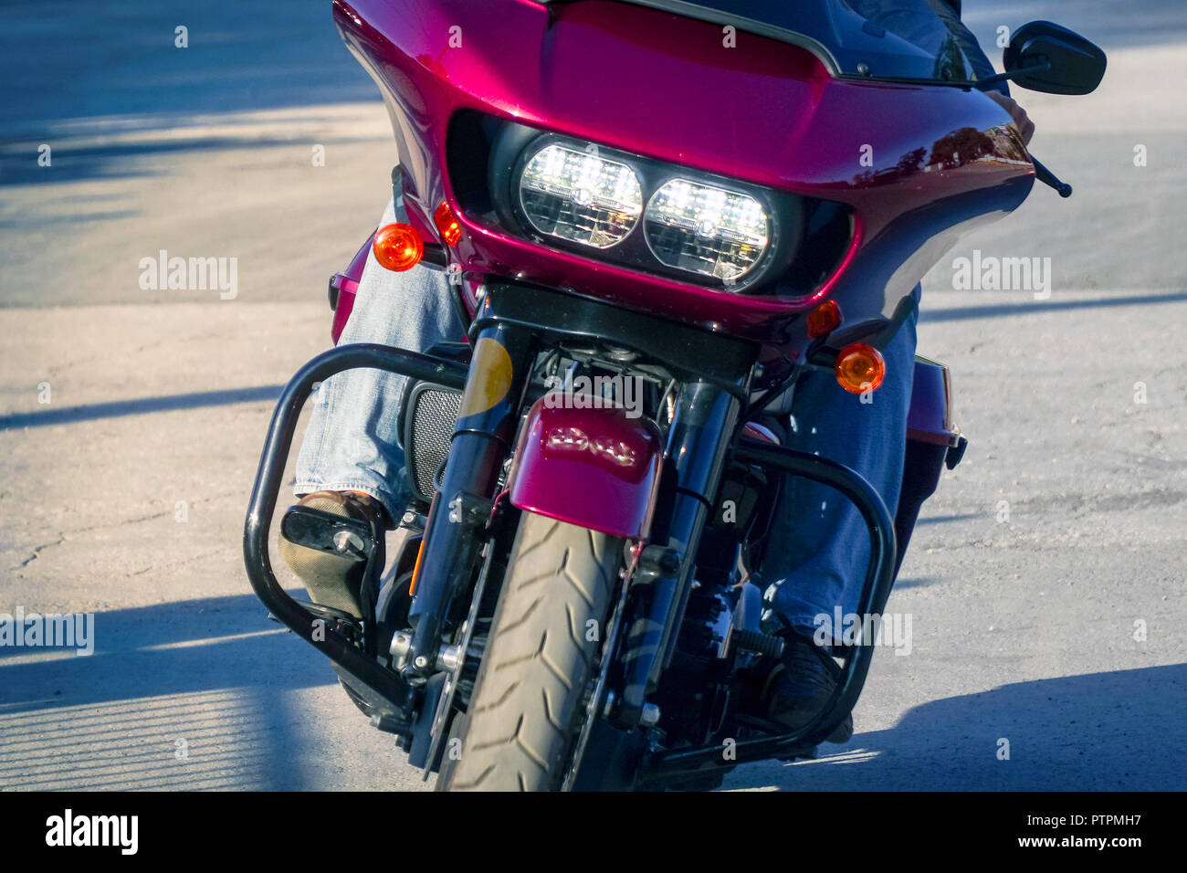 Biker in jeans riding a red motorcycle. Front view Stock Photo - Alamy