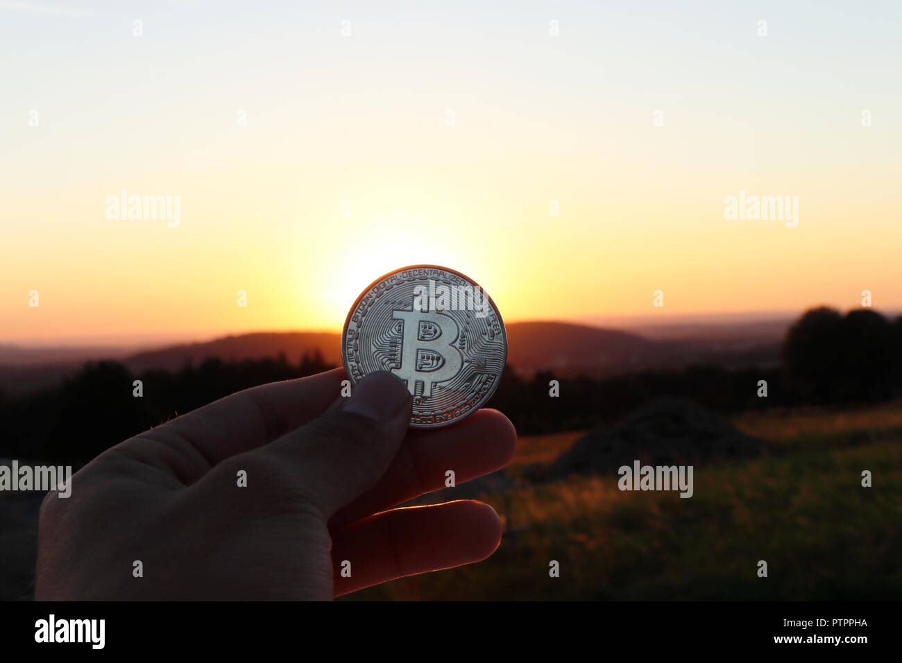 A silver bitcoin with clear blue sky and sunset. Also with beautiful ...