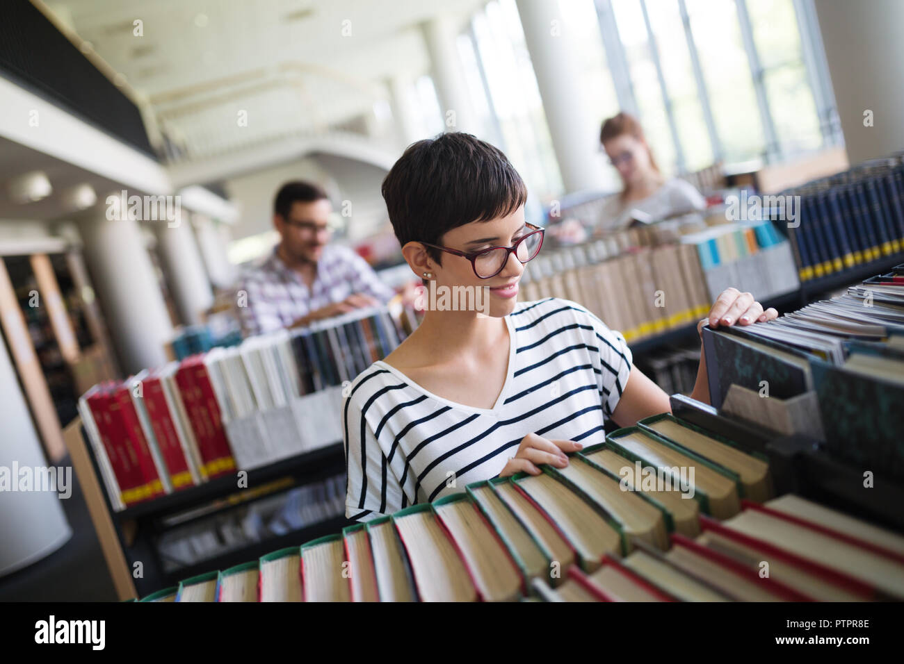 Portrait of a pretty smiling girl reading book in library Stock Photo ...