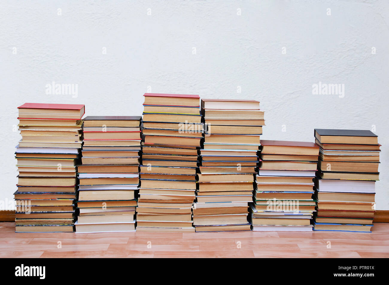 Piles of old books on the floor in a room with white walls Stock Photo ...