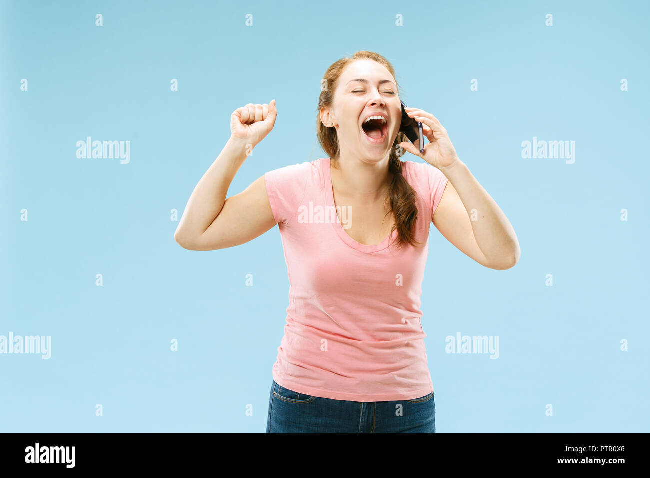 Young beautiful woman using mobile phone studio on blue color studio ...