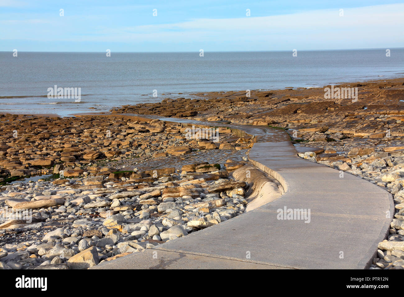 A rock strewn beach with the tide out and an access ramp in concrete ...