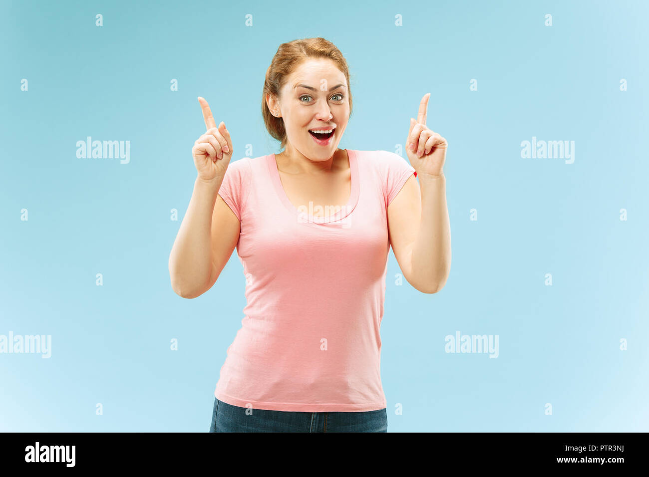 Happy business woman pointing up and smiling isolated on blue studio ...
