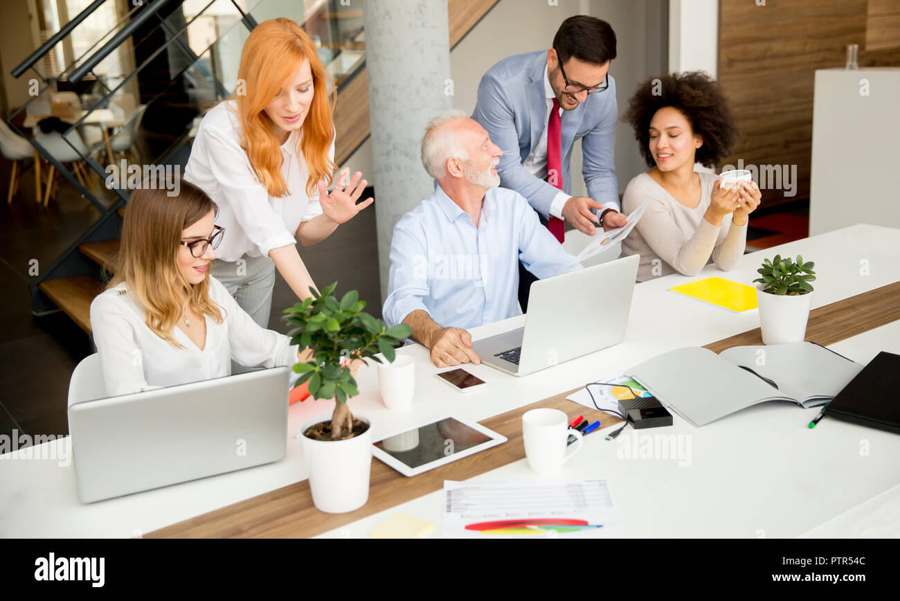 View at group of young multiracial business people around table during ...