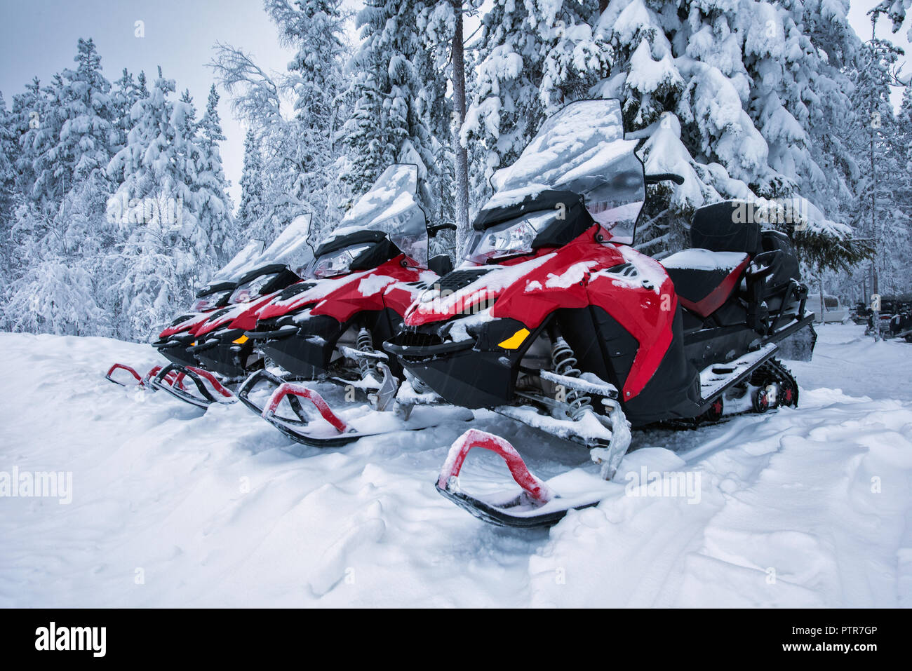 Group of four brightly colored red and black snowmobiles are ready for ...