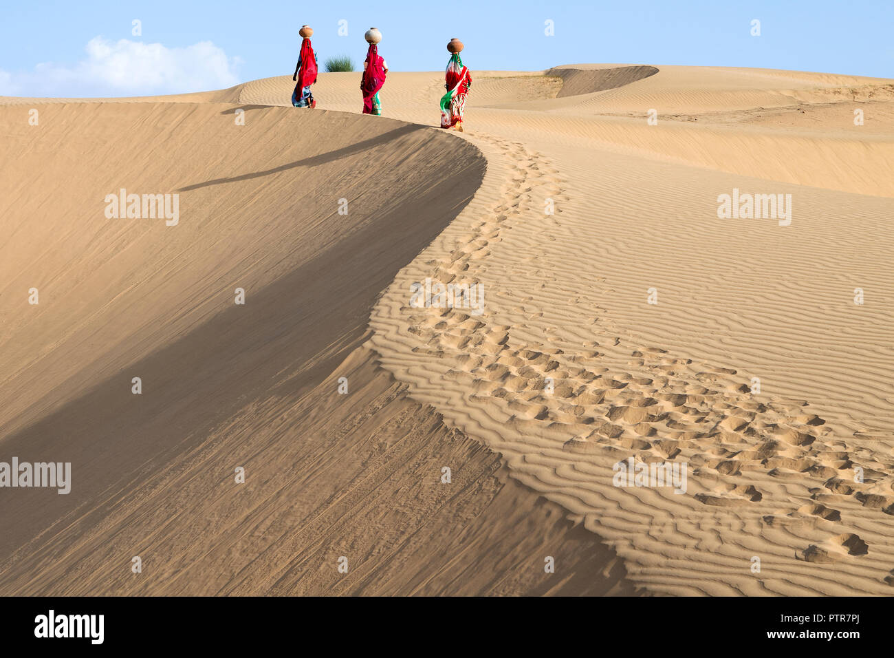 The image of Rajasthani traditional ladies with pots in sand dunes of ...
