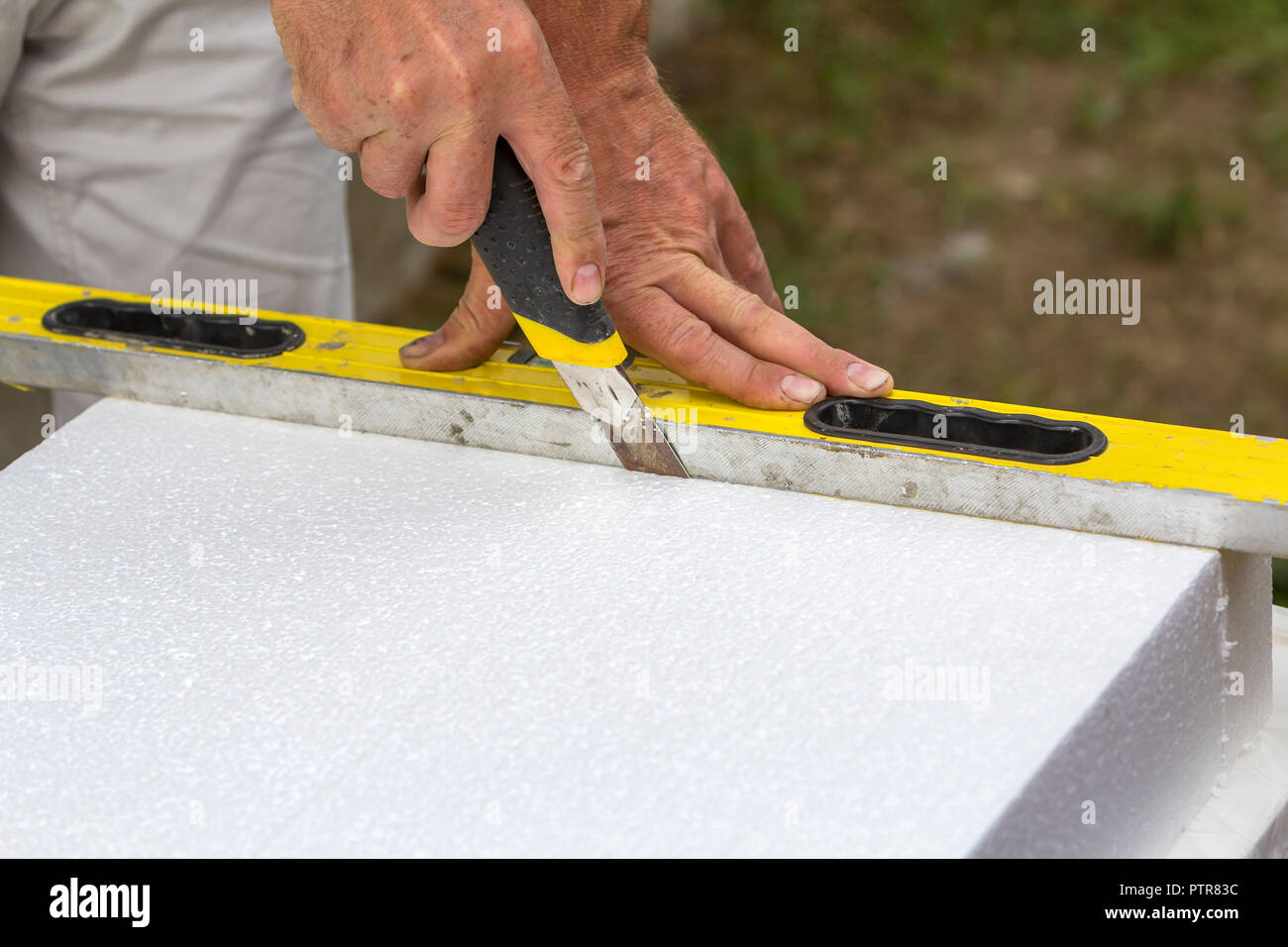 Close-up of worker hand with knife and level cutting white rigid ...