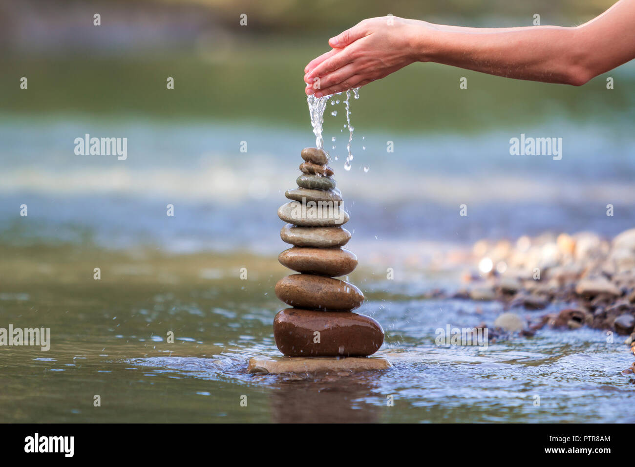 Close-up abstract image of woman hand pouring water on rough natural ...