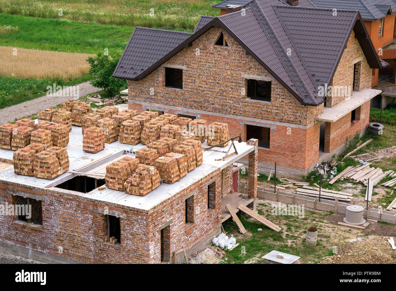 Aerial view of building site in green field. Brick basement floor of ...