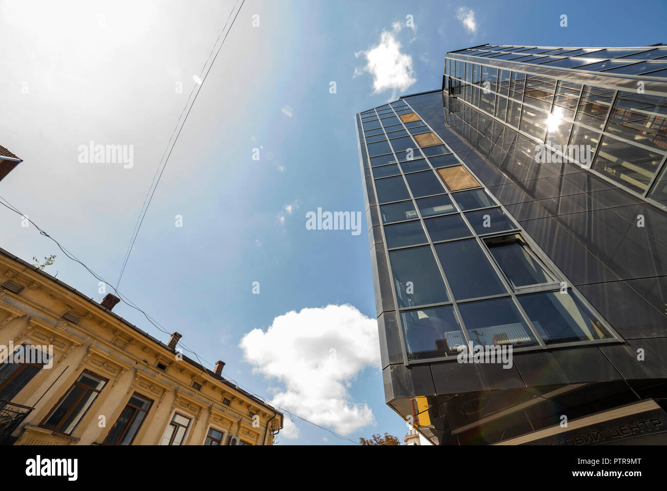 Bottom view of tall building with glass wall opposite neglected ...