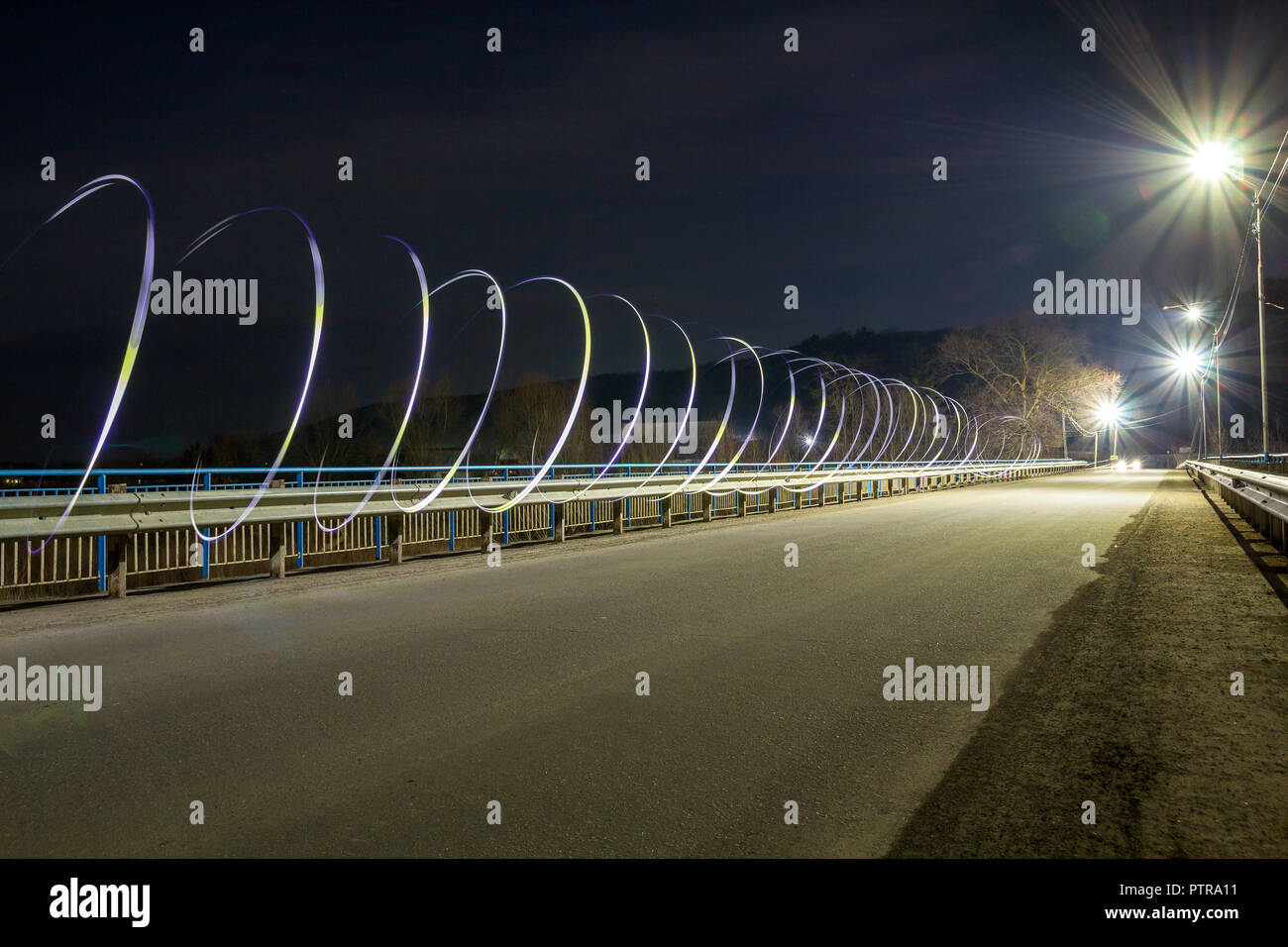 Brightly illuminated straight asphalt empty road stretching to distant ...