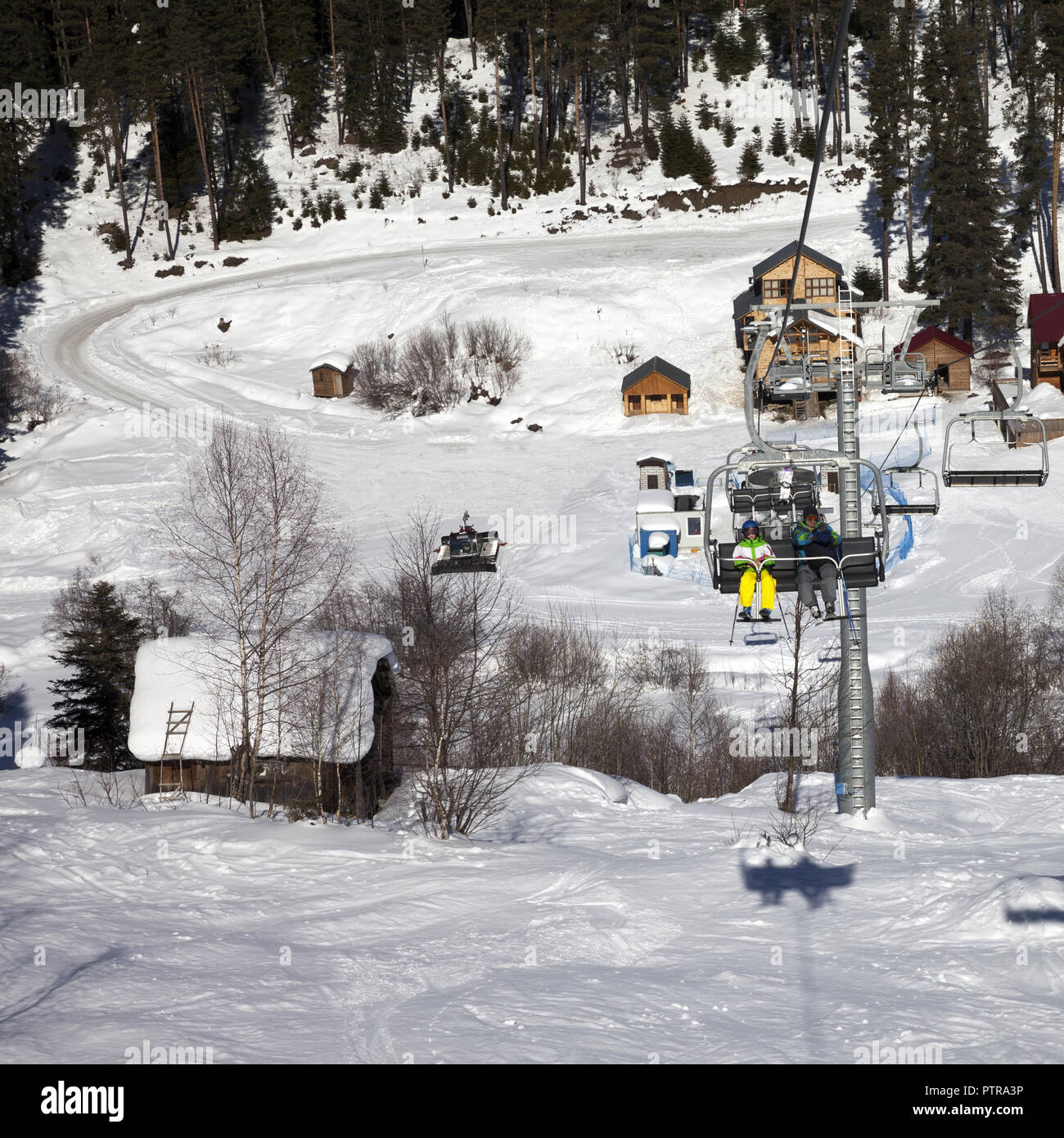 Skiers on chair-lift at ski resort in sun winter day. Caucasus ...