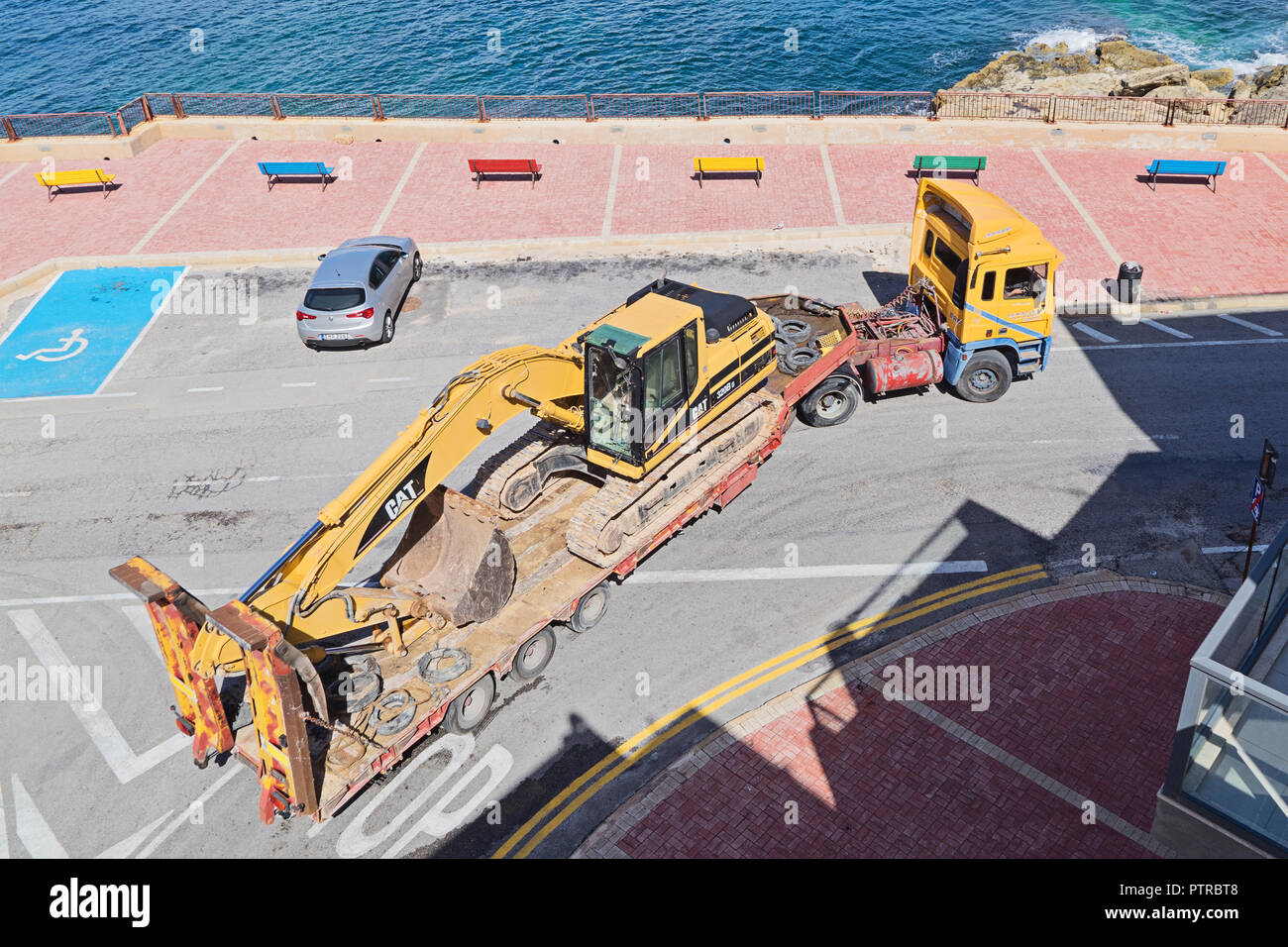 XGHAJRA, MALTA - OCTOBER 5, 2018: Large trailer transports excavator ...
