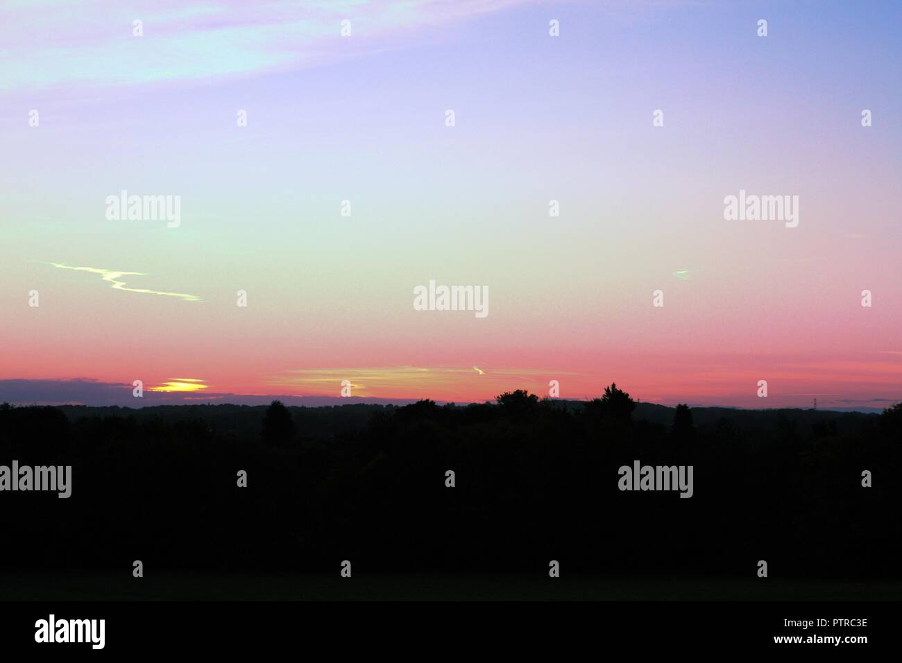 Sun Rising over silhouetted tree lined horizon Stock Photo - Alamy