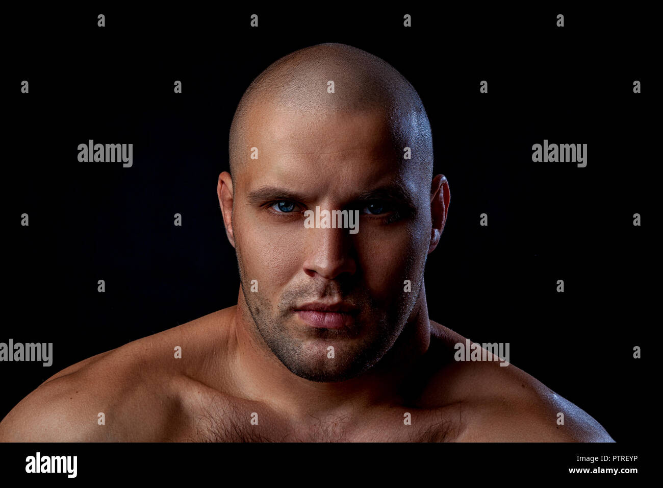 serious young bald man standing isolated on a black background and ...