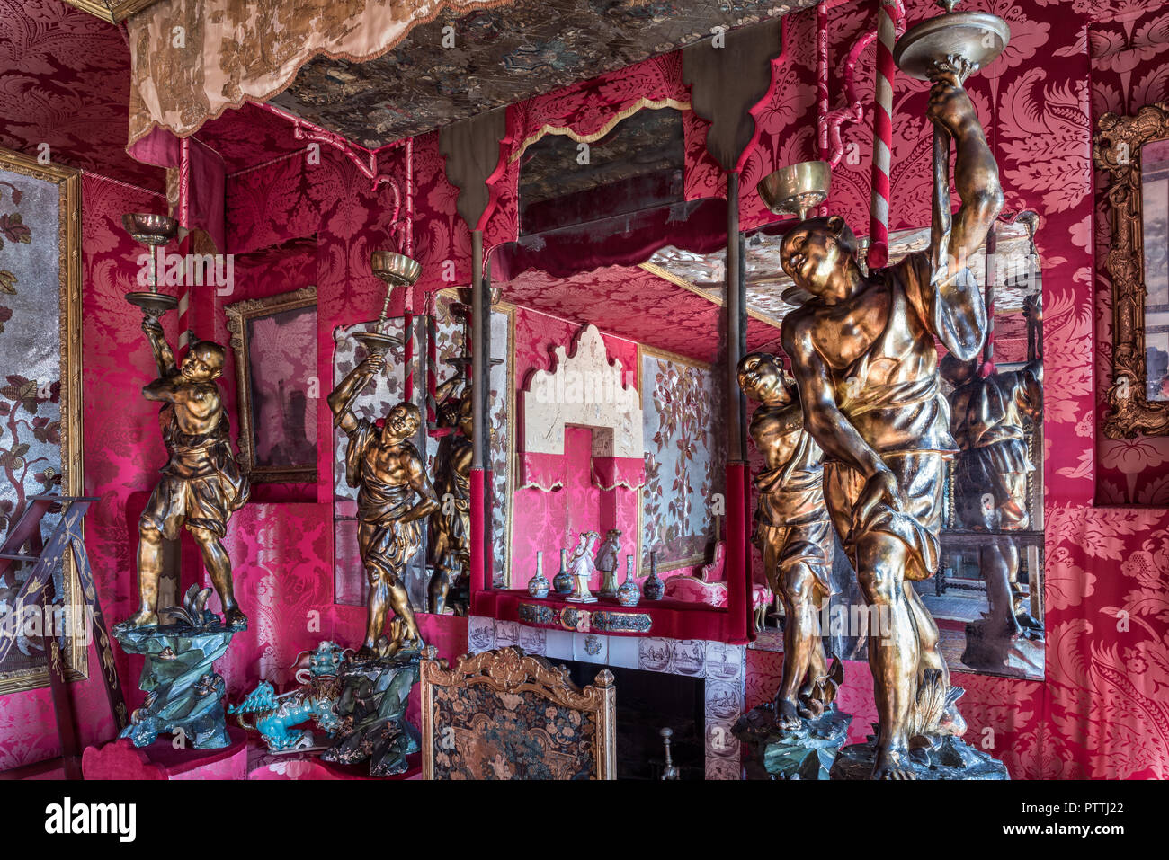 Gold torch-bearers with mirror and red damask wall covering in ...