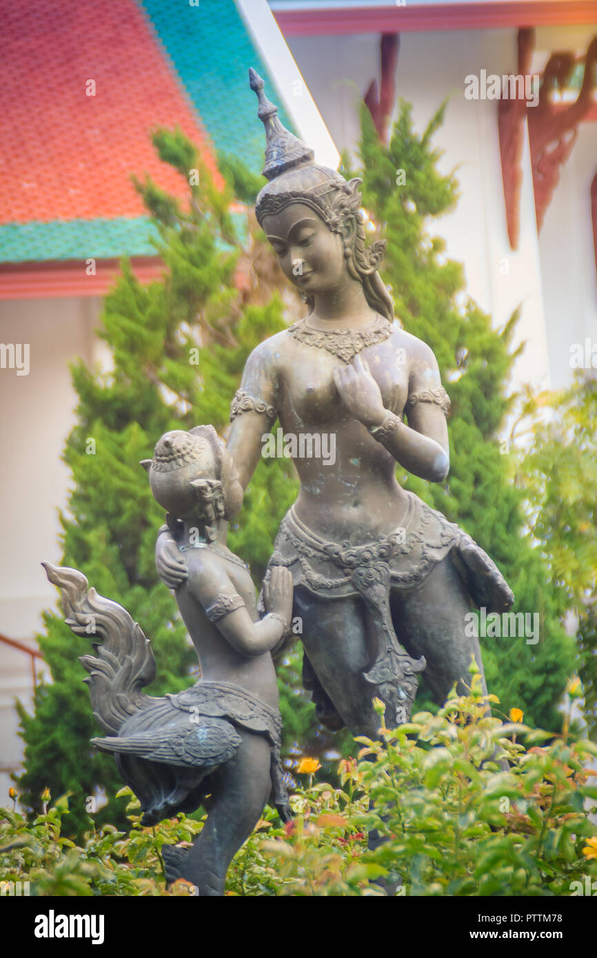 Cute bronze mother and son kinnaree sculptures in the green garden at ...