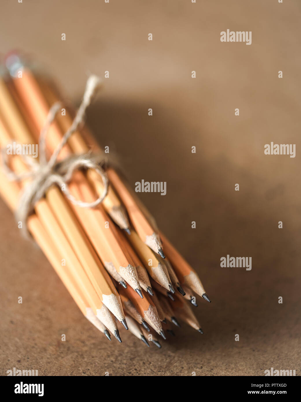 a stack of graphite pencils tied with rope on wooden background ...
