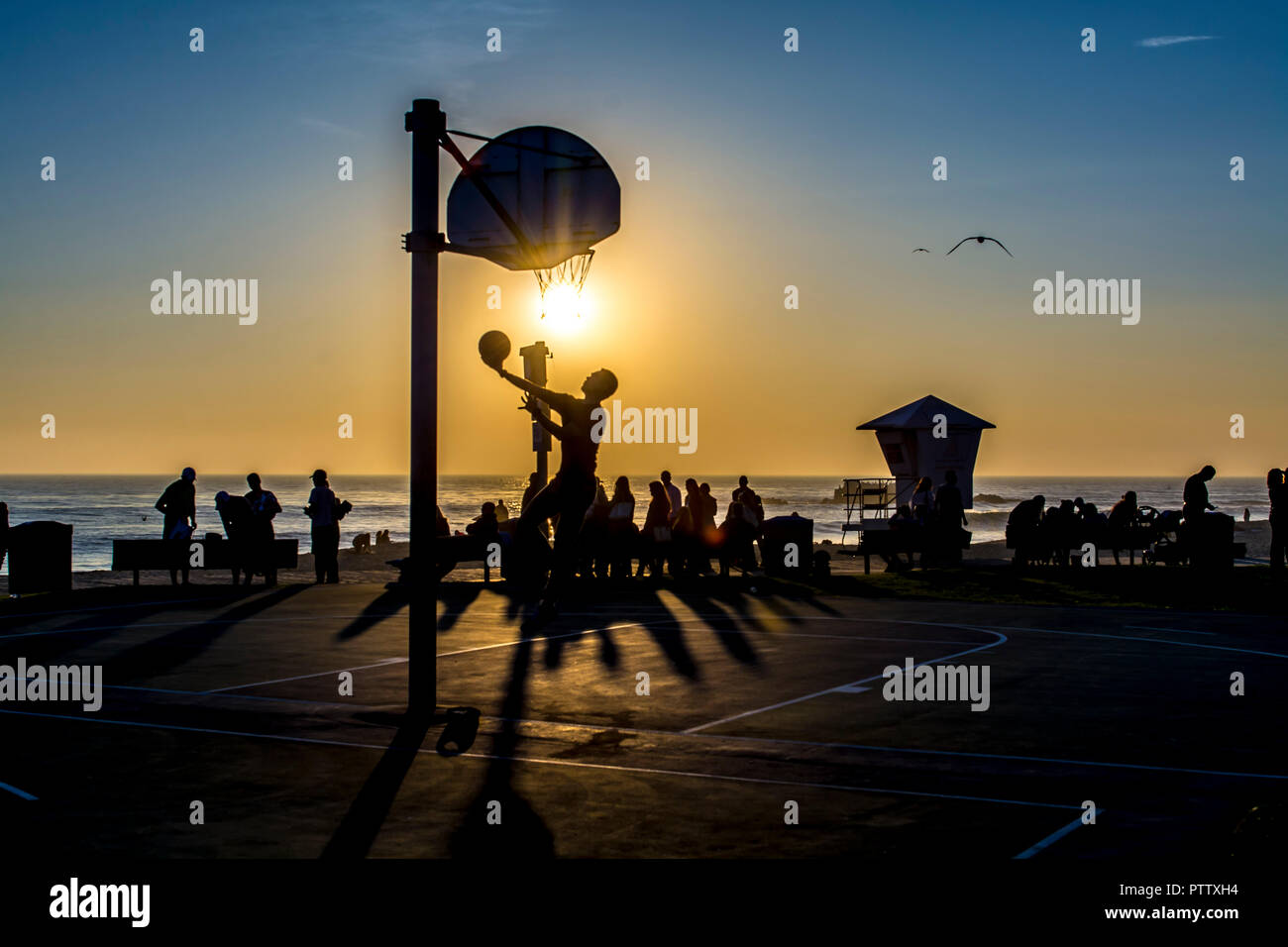 Man playing basketball during sunset at the beach Stock Photo - Alamy
