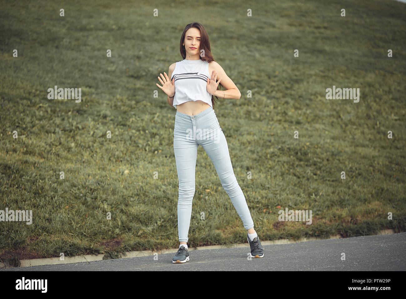 a young girl dancing on the street in the summer in the city against ...
